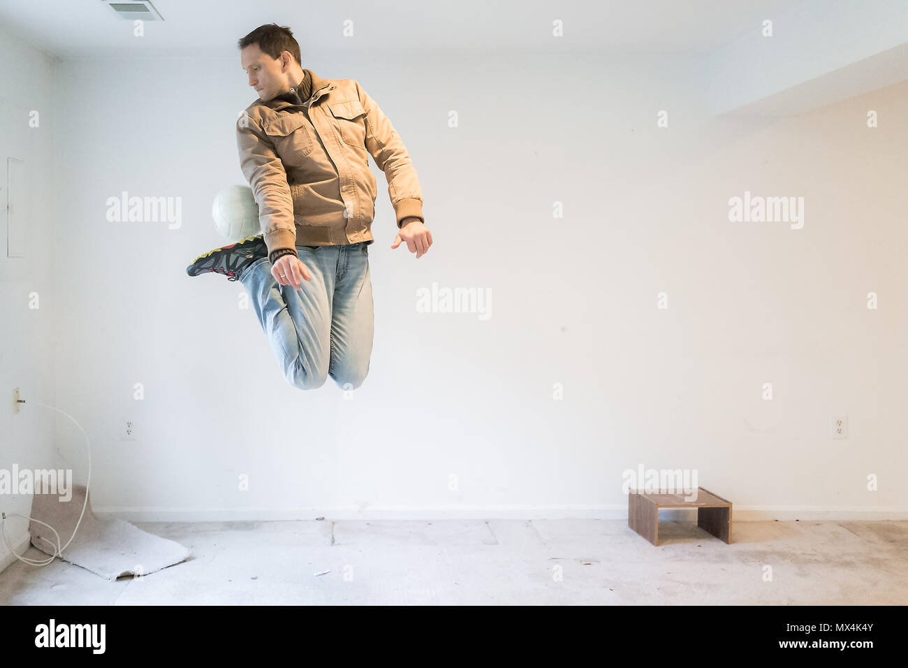 Young skilled man jumping up performing mid-air trick with soccer ball ...