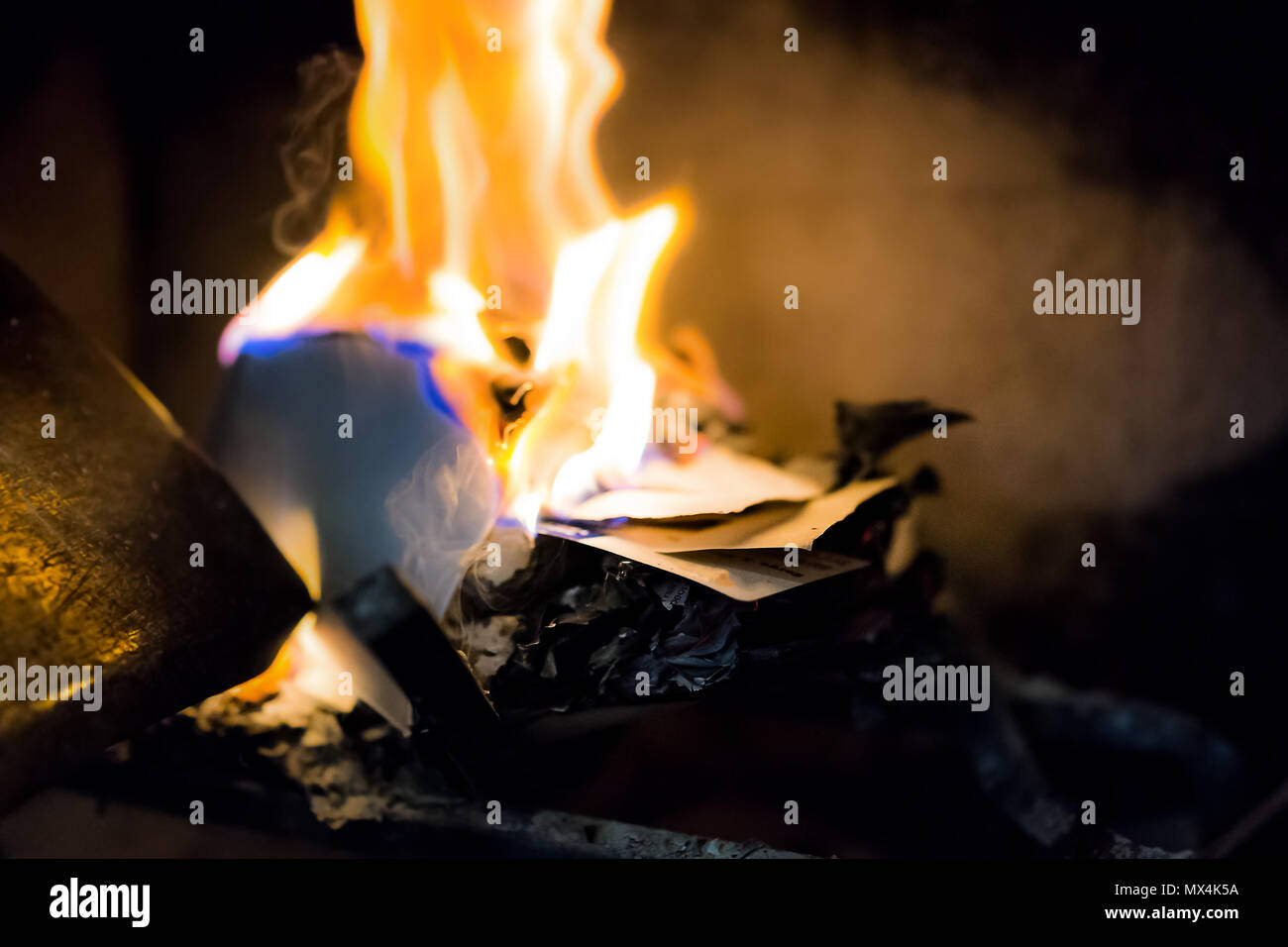 Burning paper, letters in indoor home interior fireplace with closeup ...