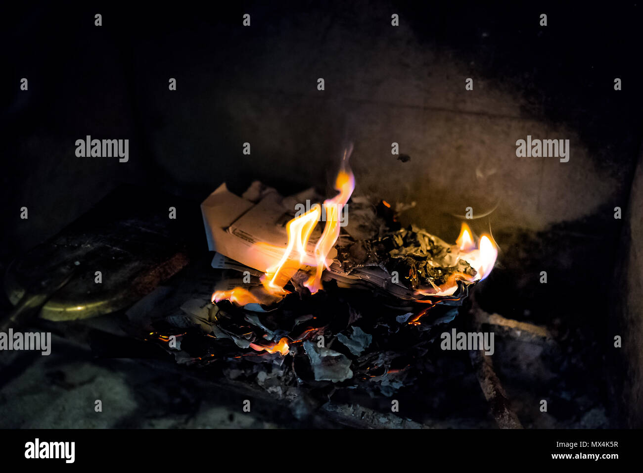 Burning paper, letters in indoor home interior fireplace with old retro ...