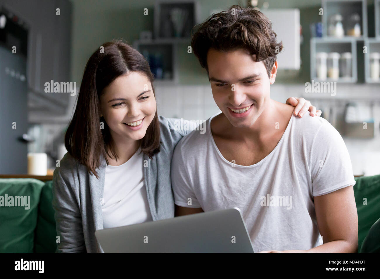 Happy millennial couple smiling looking at laptop screen making Stock ...