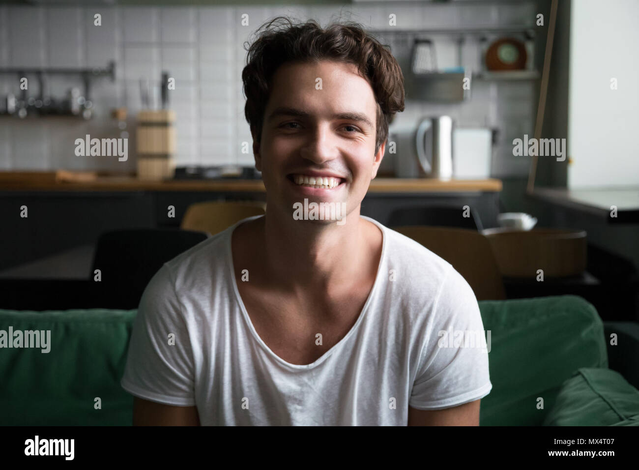 Smiling man looking at camera sitting on kitchen sofa, portrait Stock ...