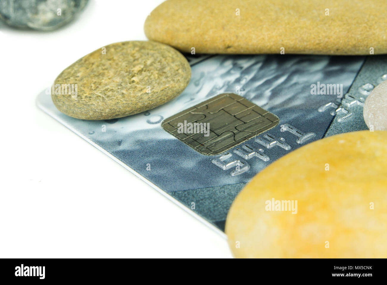 grey debit card is laying under various pebble stones Stock Photo - Alamy