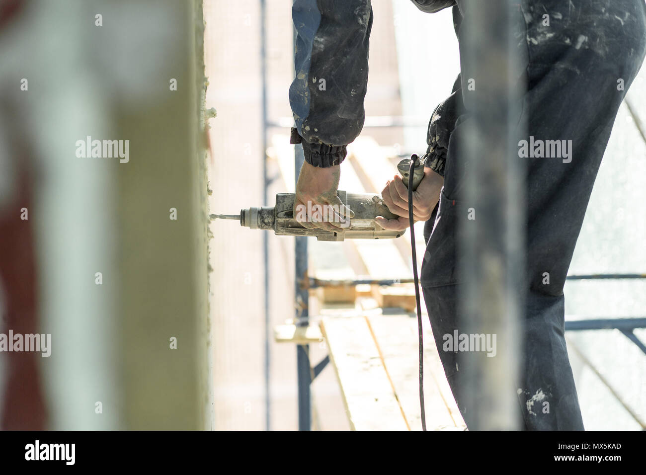 Hand drilling on the scaffolding on altitude. Concept repairing the ...