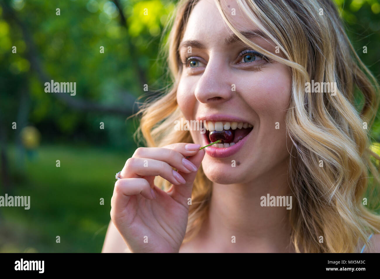 Girl eating cherries in outdoor park Stock Photo - Alamy