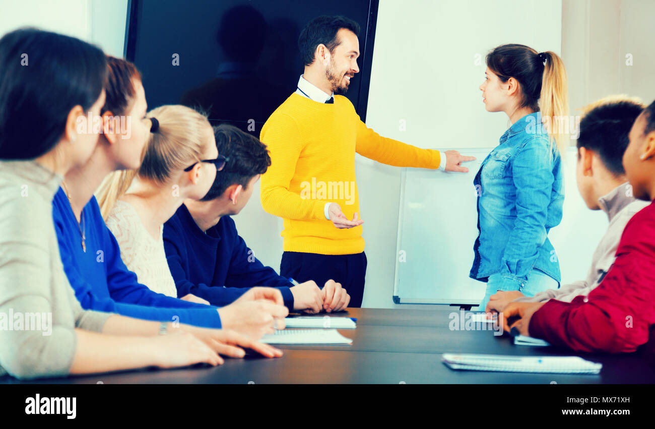 Diligent serious female student answering teacher’s question at writing ...