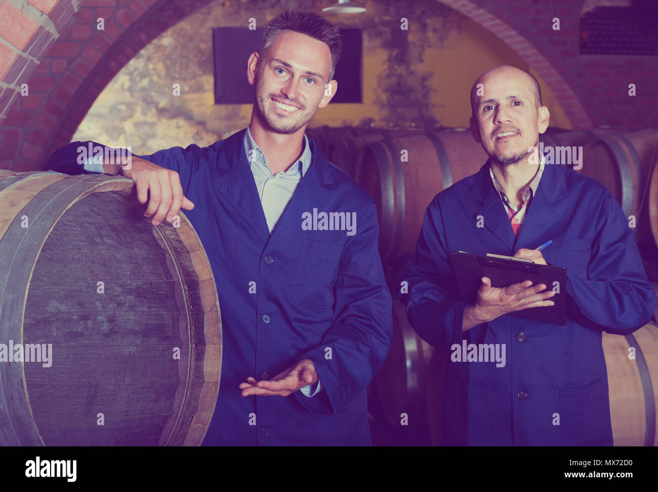 portrait of two smiling male wine makers wearing coats standing with ...