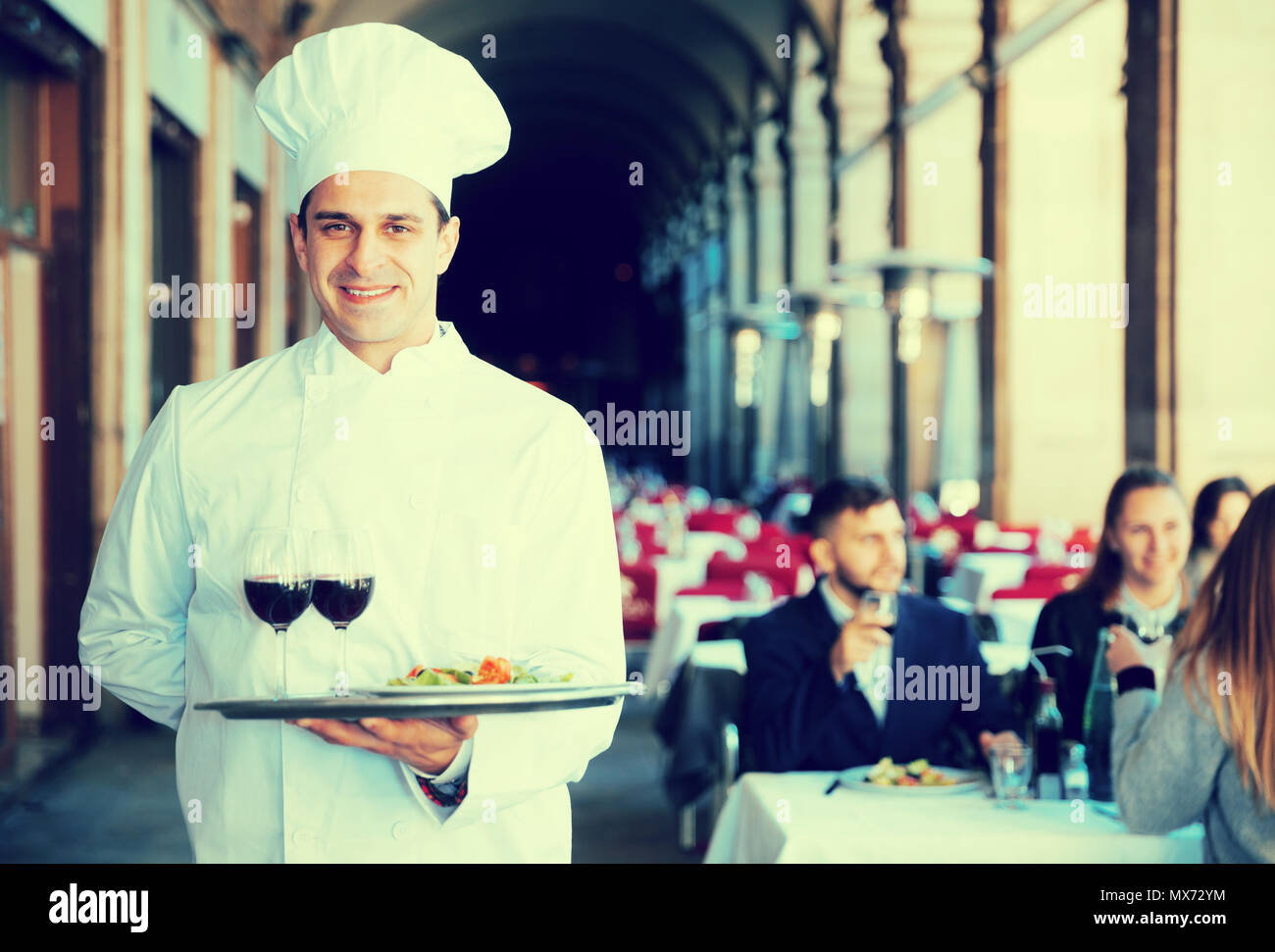Handsome male chef with serving tray welcoming to restaurant Stock ...