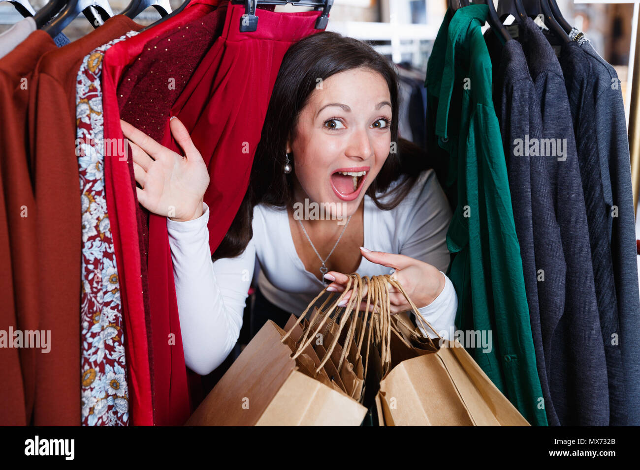 Positive cute girl customer delighted between the handles in the store ...