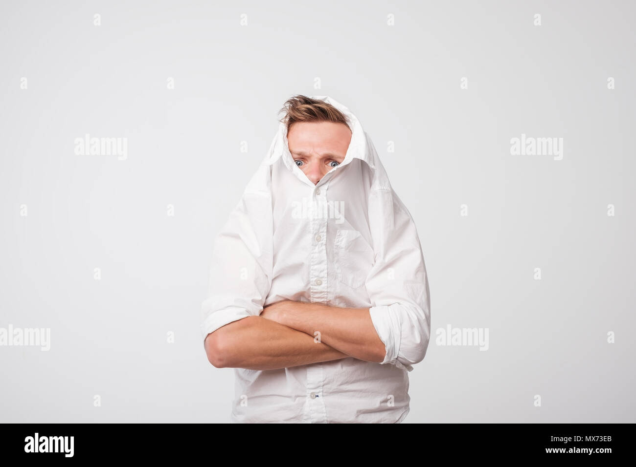 Angry caucasian man pulls a white shirt over his head. loneliness of ...