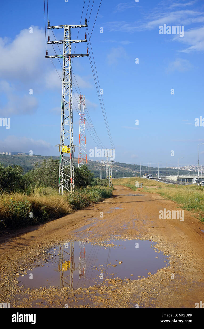 Electrical pylons and pools on the dirt road Stock Photo - Alamy