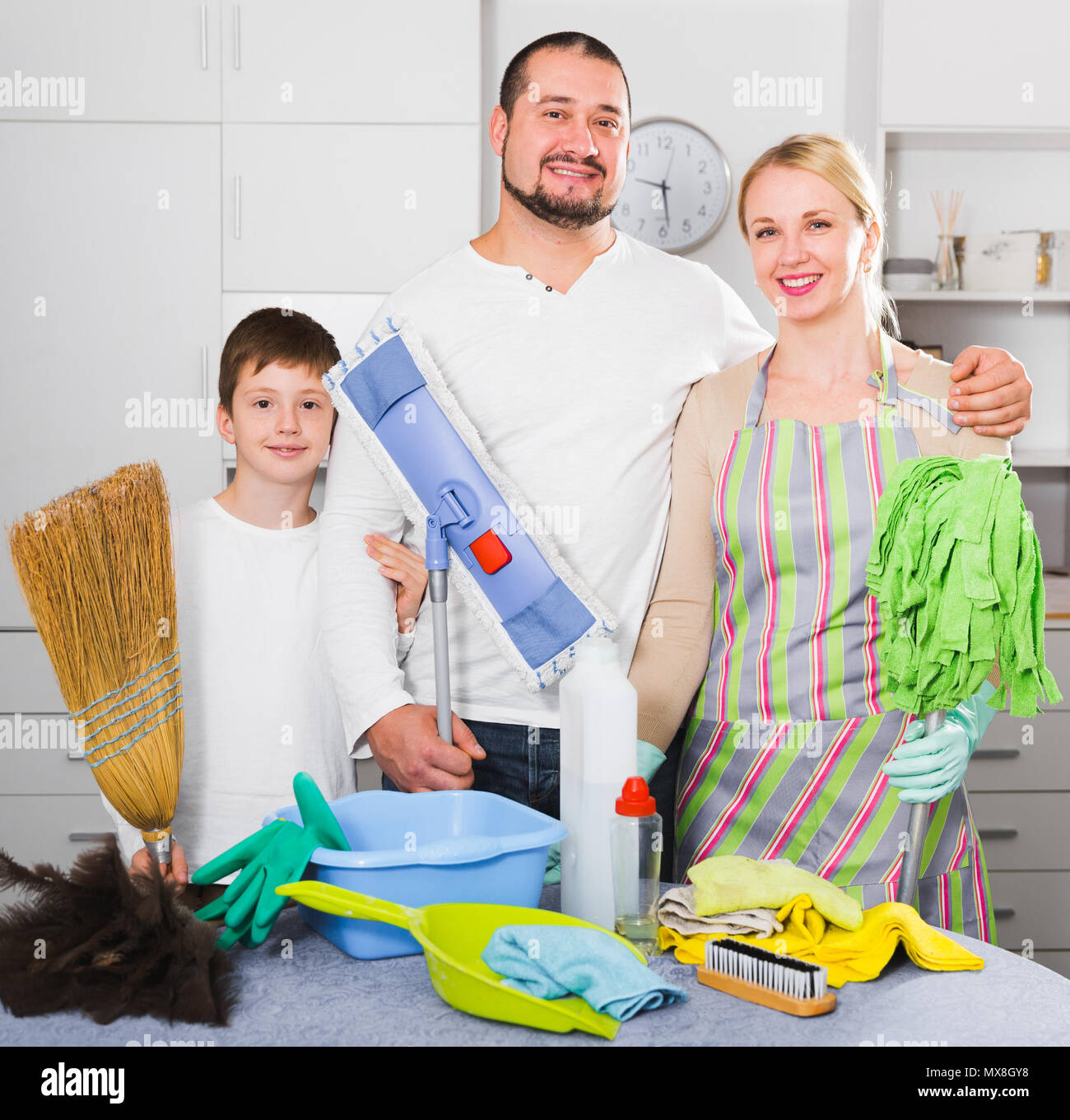 Portrait of friendly smiling family standing at room ready to clean ...