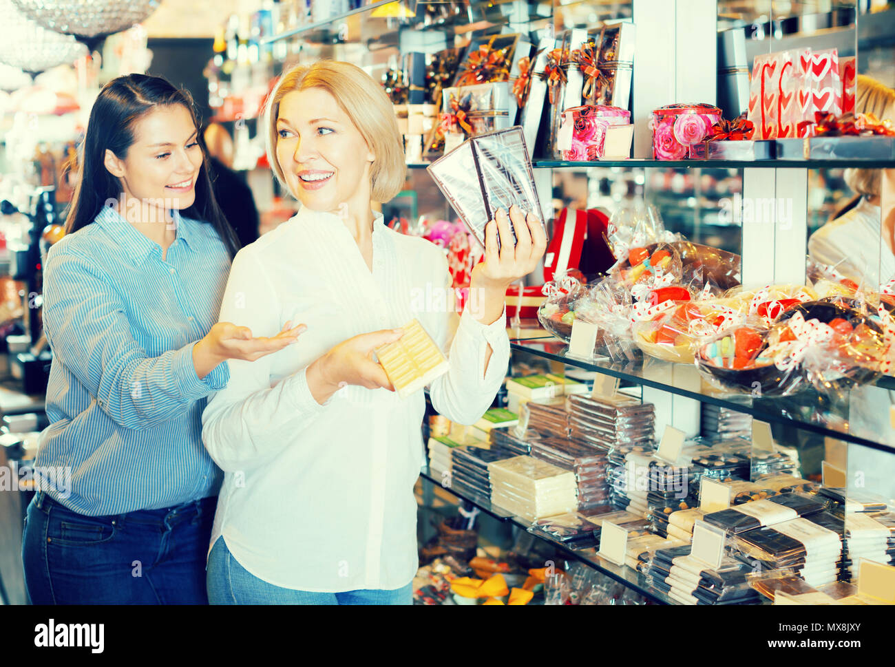 Female customers choosing delicious milk chocolate in shelf Stock Photo ...