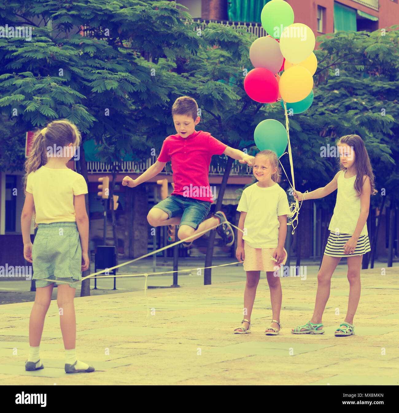 Laughing kids in school age playing together with chinese jumping rope ...