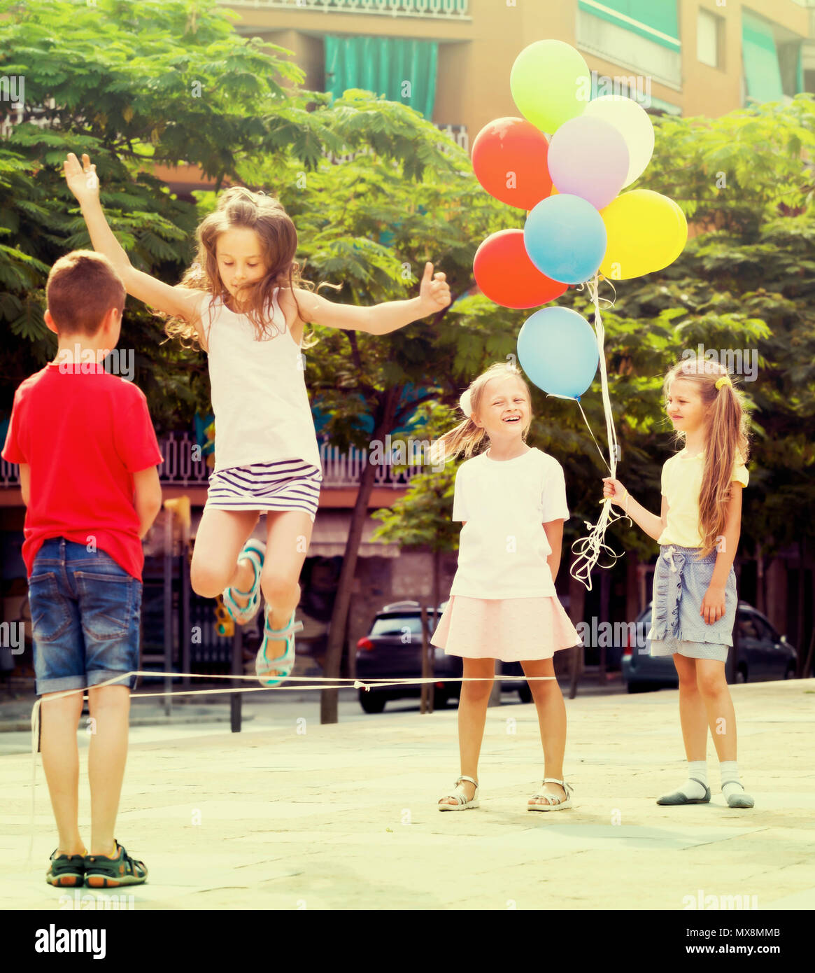 Friendly kids in school age playing together with chinese jumping rope ...