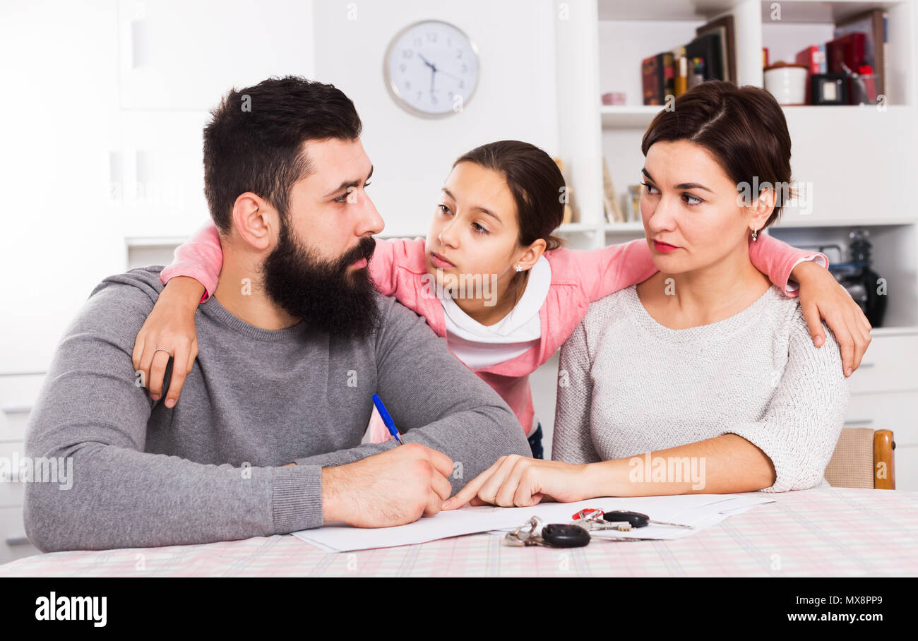 Young sad parents signing papers for divorce while their daughter at ...