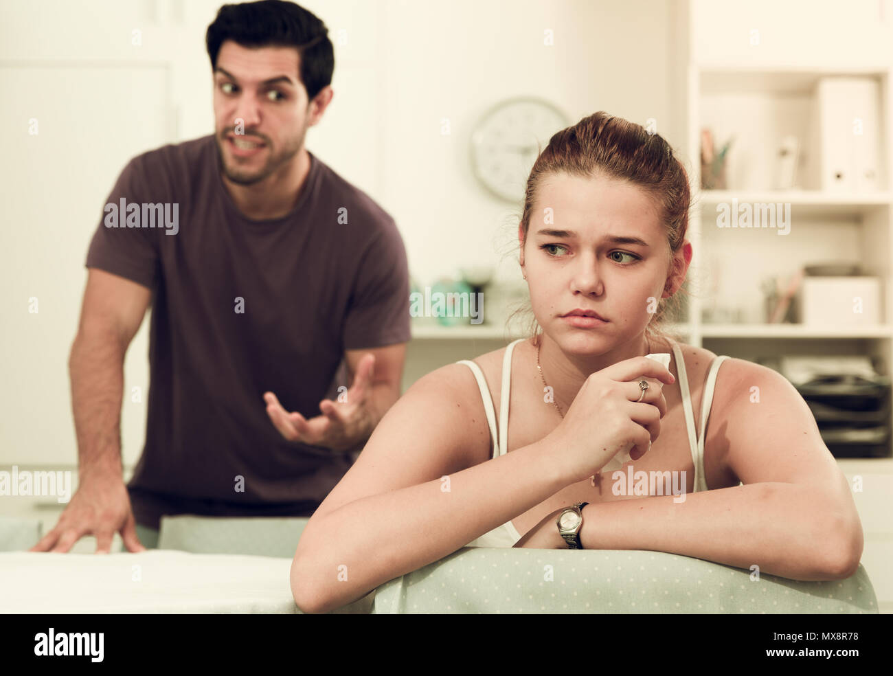 Frustrated girl sitting at home table on background with angry ...