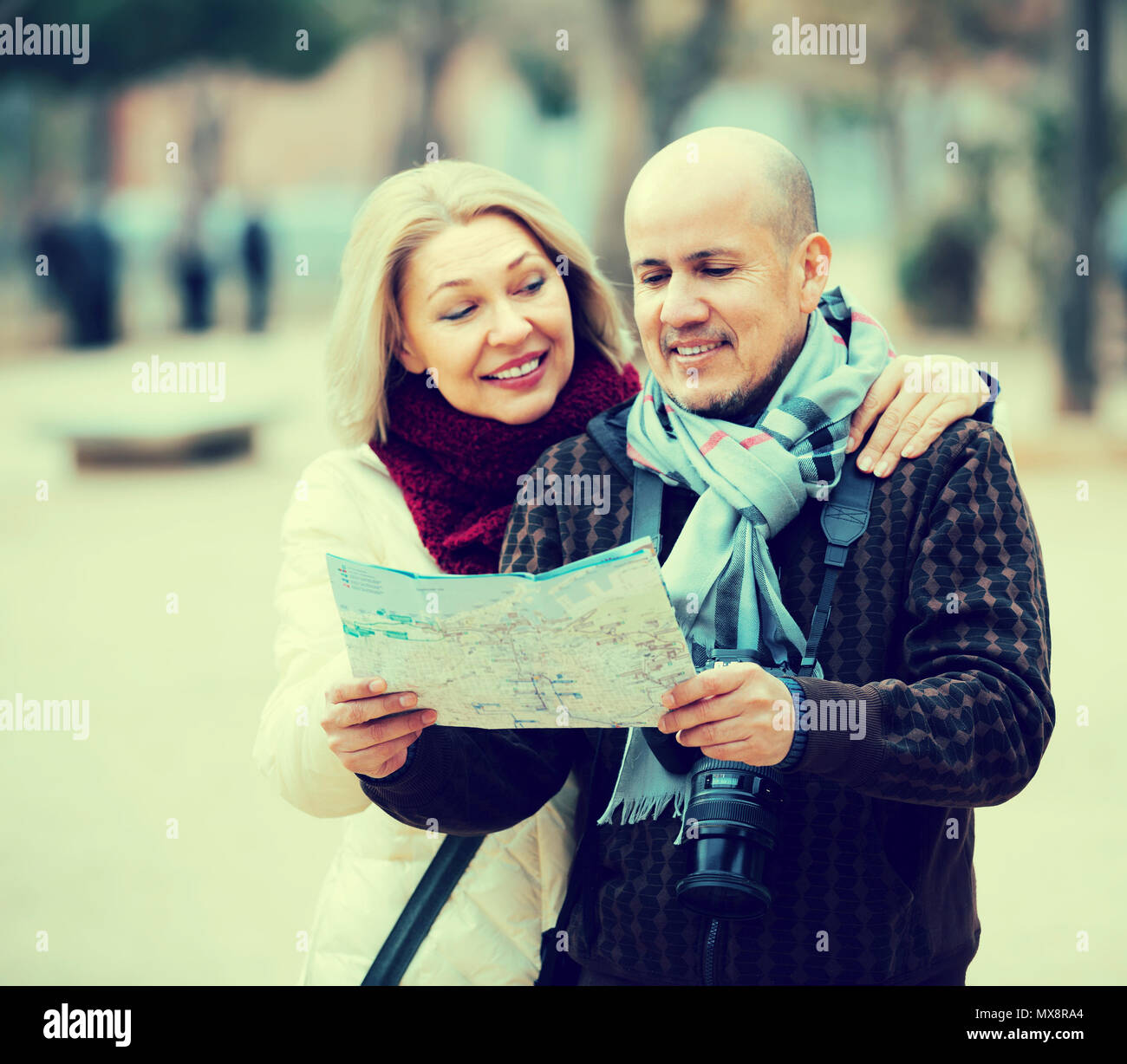 Cheerful senior couple of travellers looking in map for correct ...