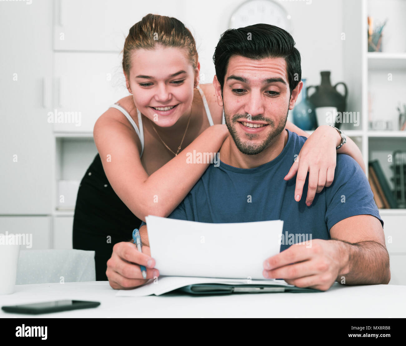 Happy young man and woman reading mail together and checking ...