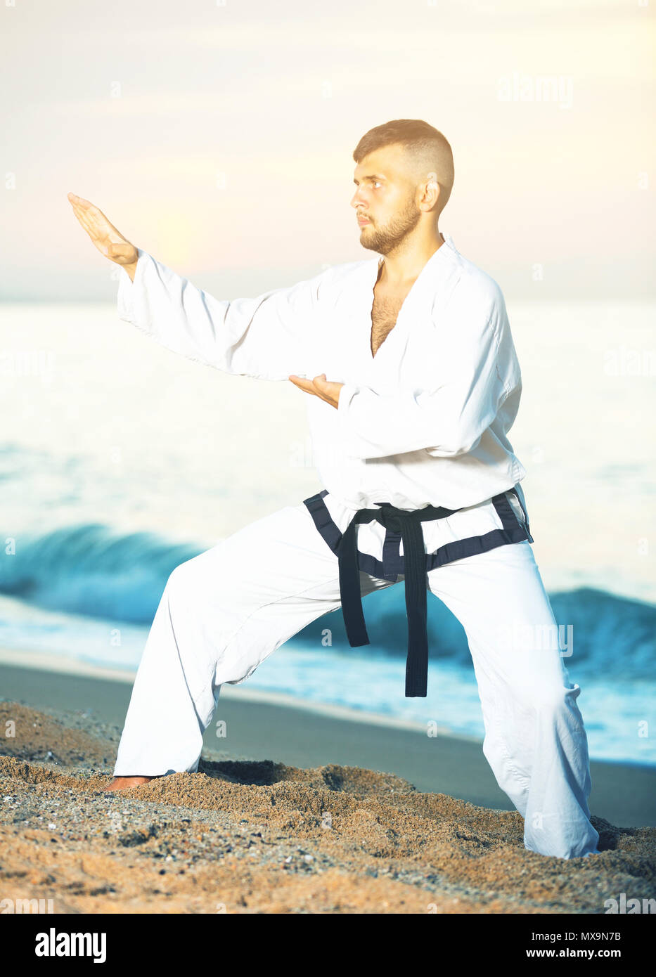 Sportsman is training the Shiko-dachi stance on the beach near the sea ...