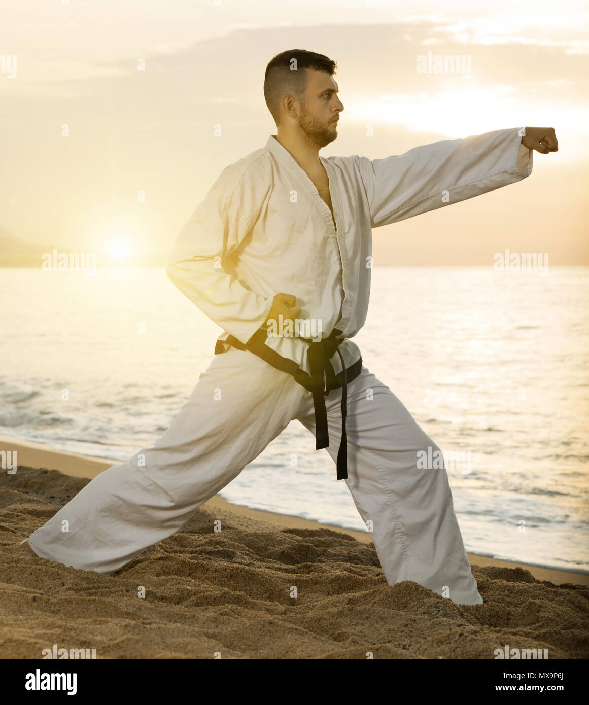 Positive young guy doing karate poses at sunset sea shore Stock Photo ...