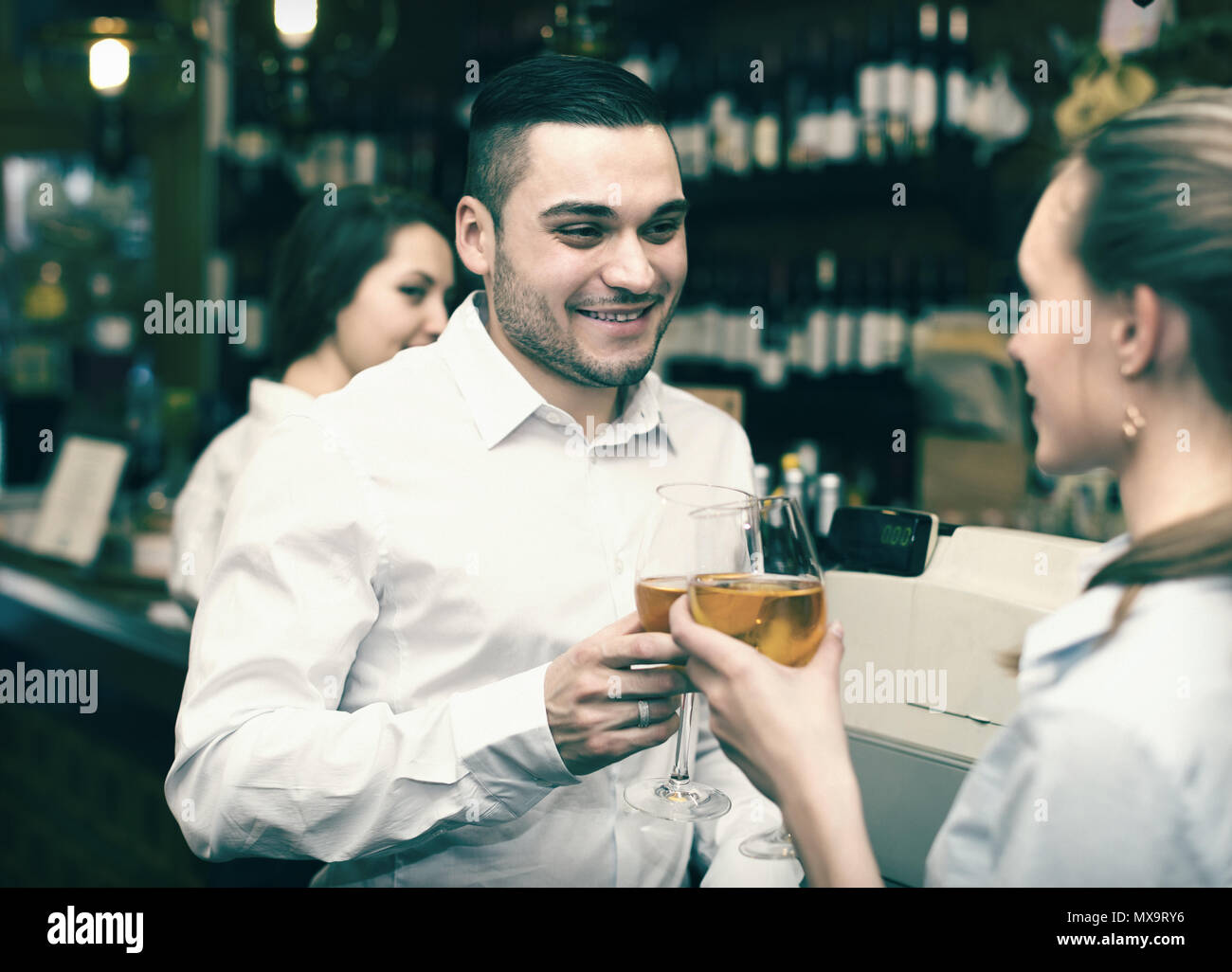 Smiling restaurant visitors waiting for table and drinking wine at bar ...