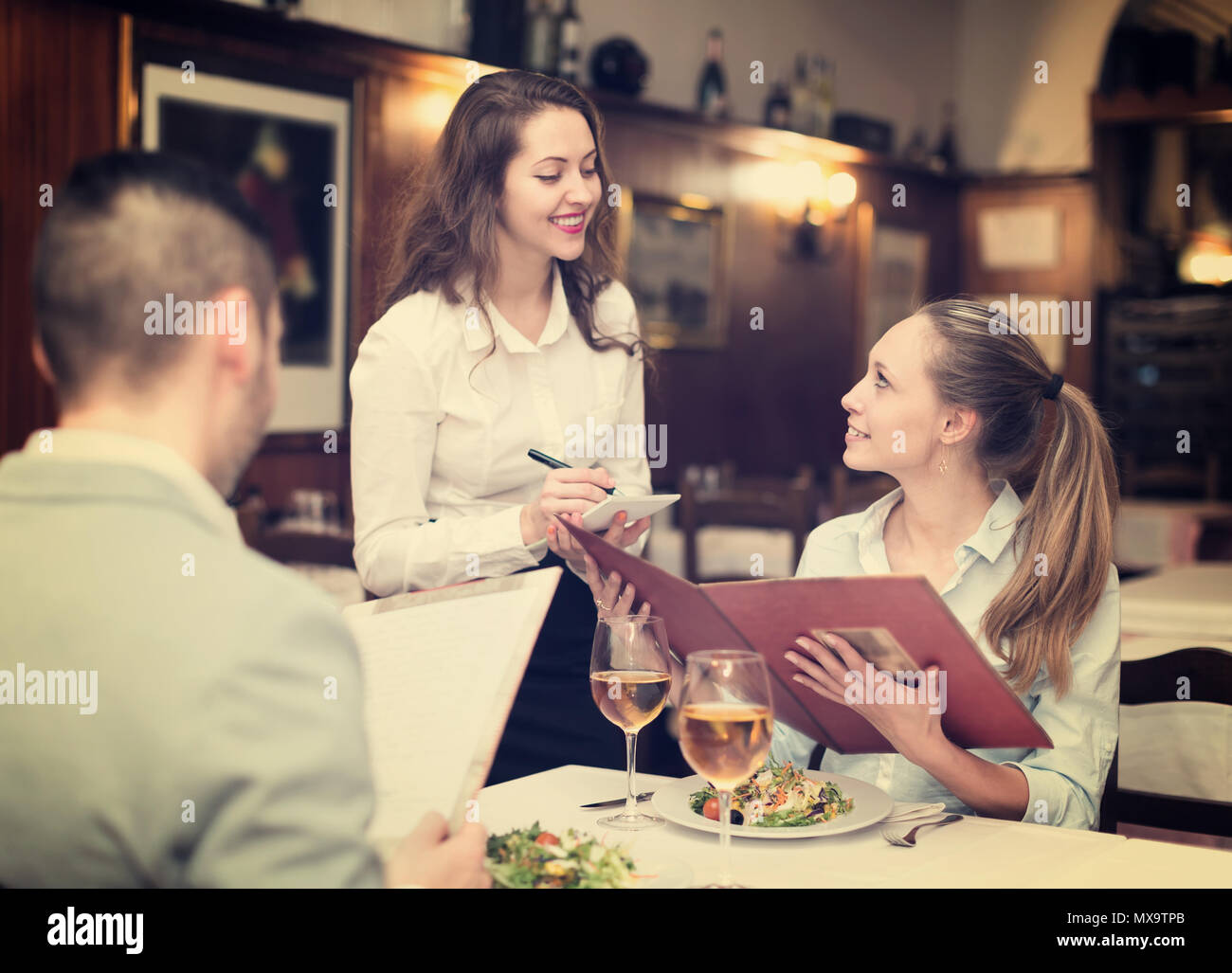 Hospitable waitress taking an order from a couple in a rural restaurant ...