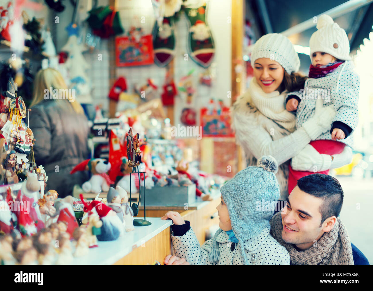 A handsome man with his wife and children shopping at a christmas fair ...