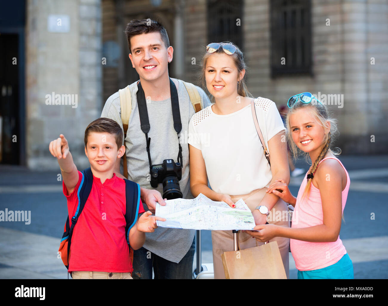 Positive young parents with two kids traveling together searching ...