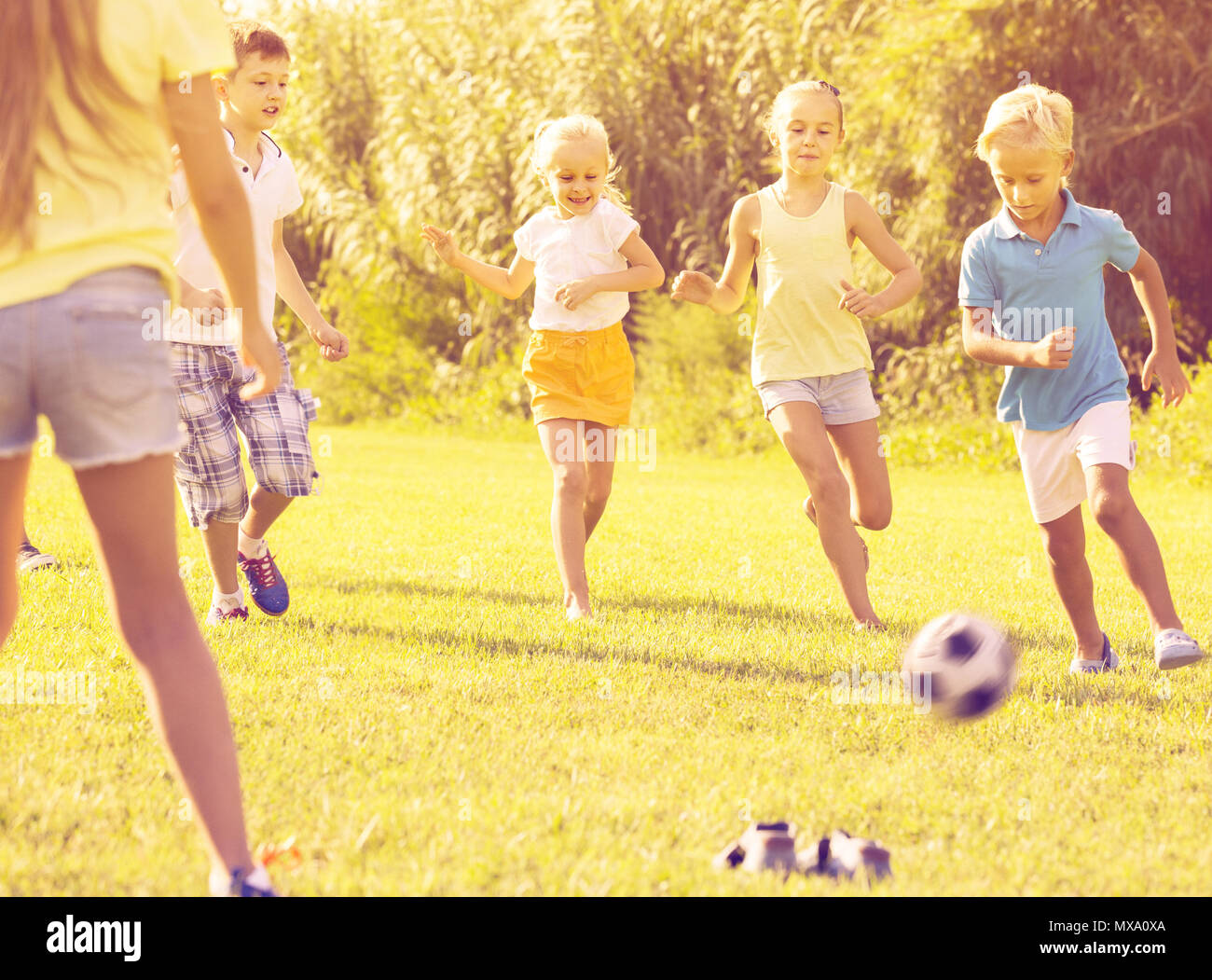 active kids having fun and kicking football in park on summer day Stock ...