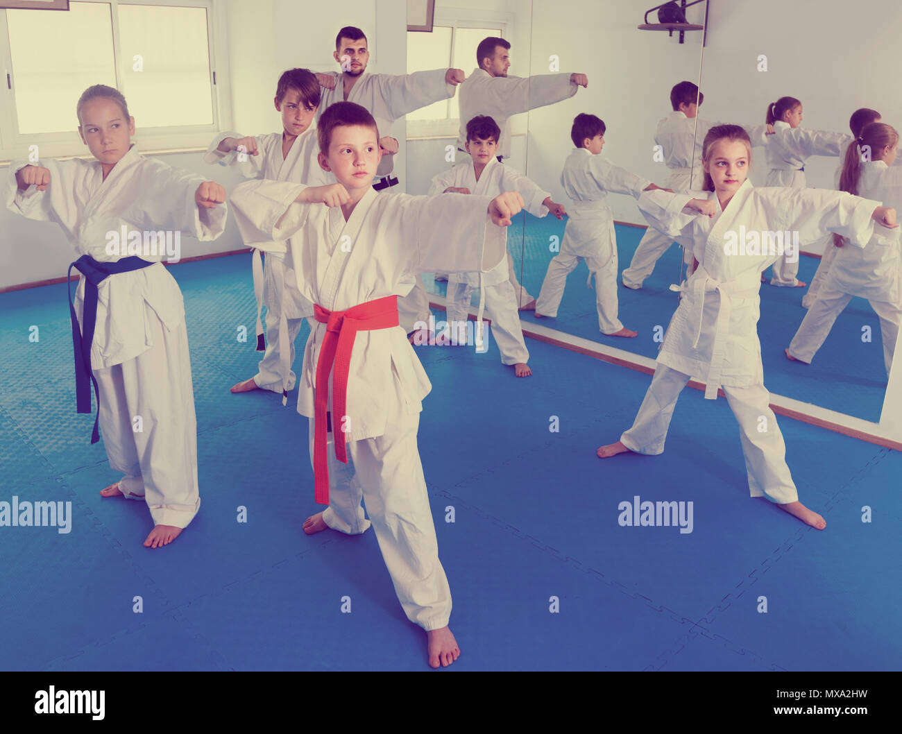 Young children training karate kicks with master during karate class ...