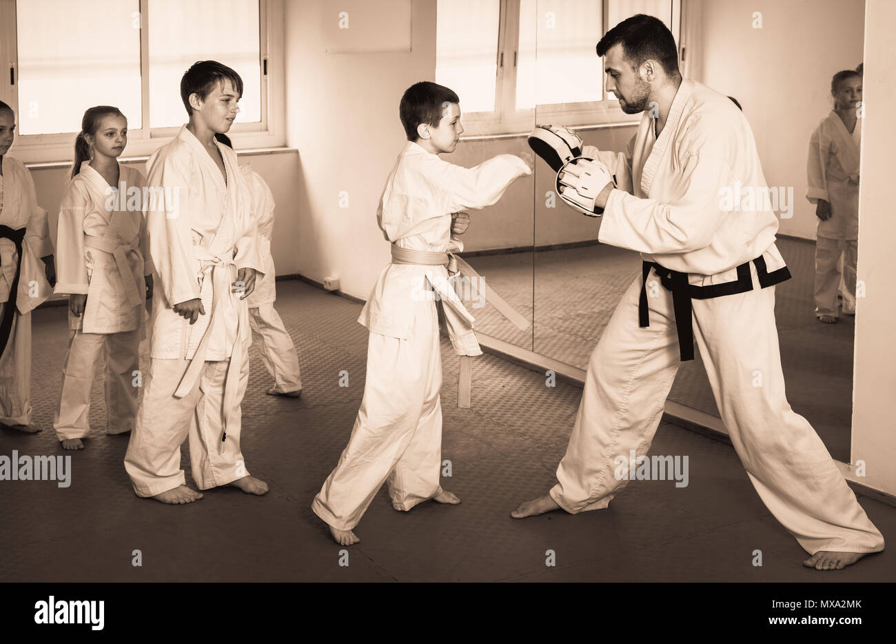 Young boys training karate kicks with coach during karate class Stock ...