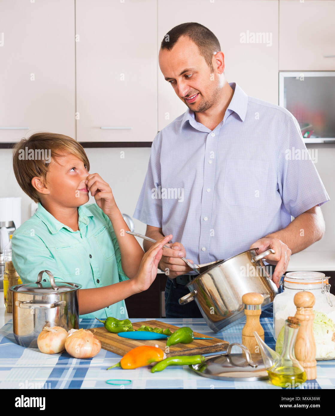 Father and his teenage son cooking the dinner and smiling Stock Photo ...