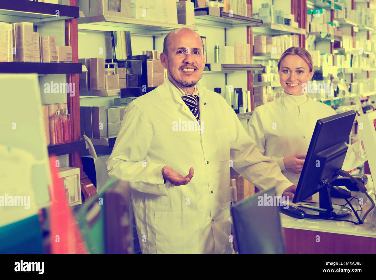 Two female and male pharmacists in white coats working the pharmaceutical store Stock Photo - Alamy