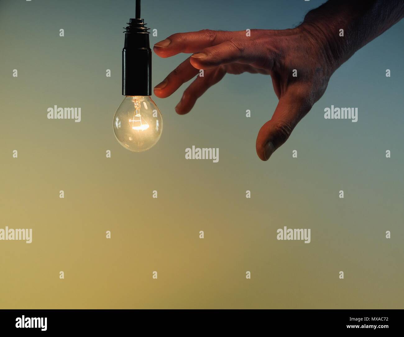Incandescent light bulb with male hand on a blue and yellow background ...