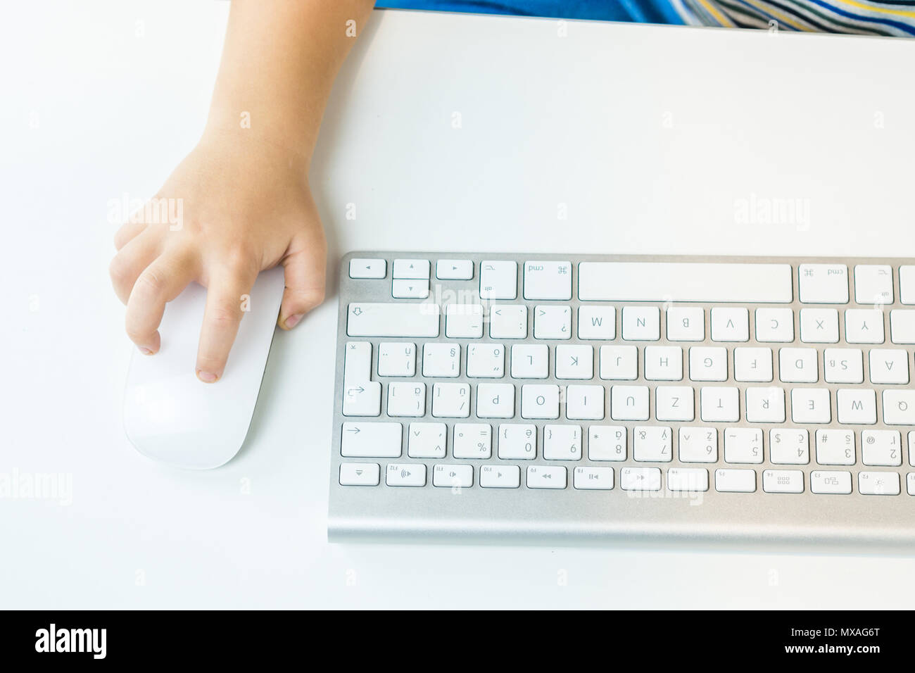 young boy is sitting on chair and working seriously with computer mouse ...