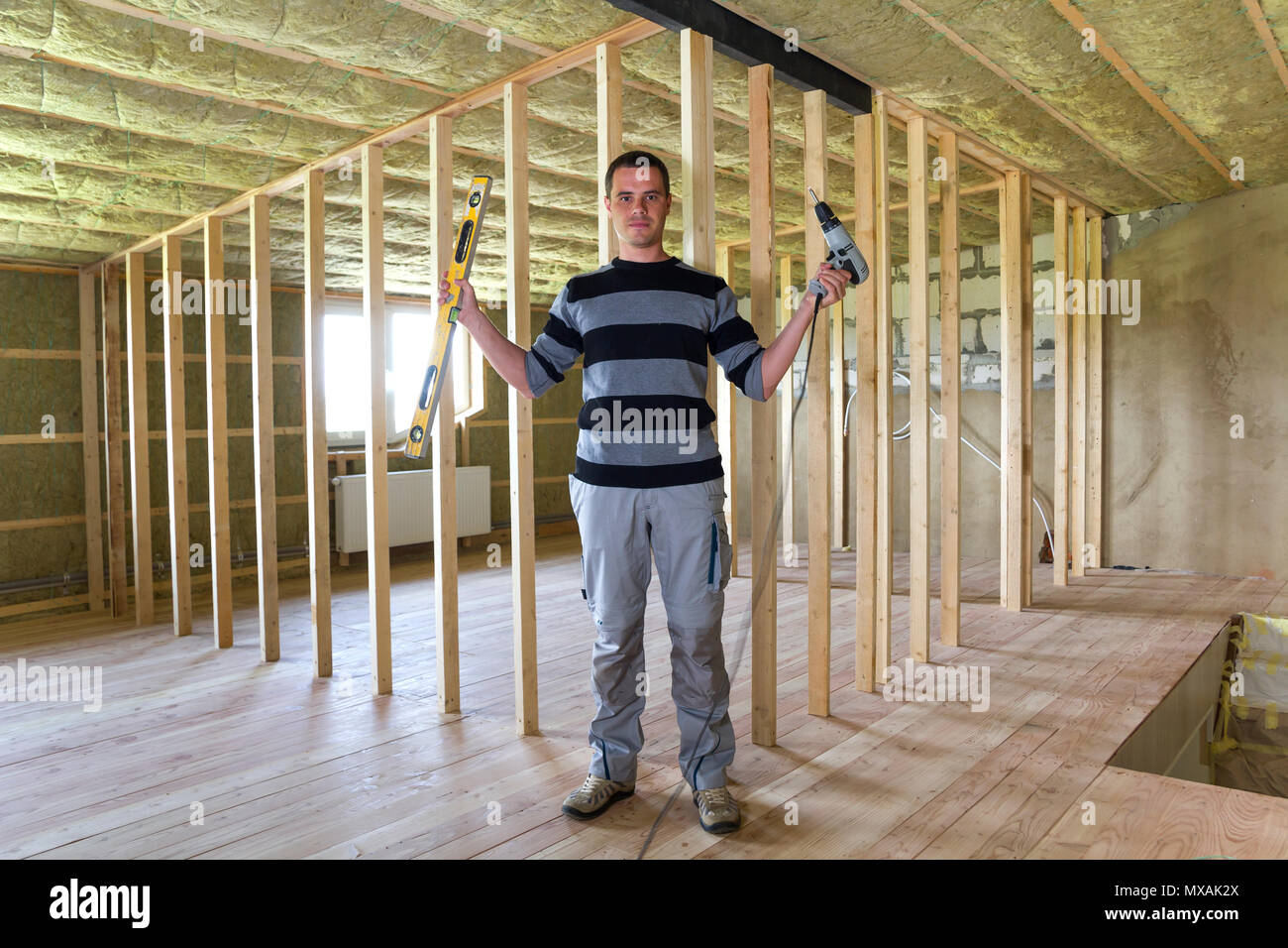 Young handsome worker with level and screwdriver looking in camera in ...