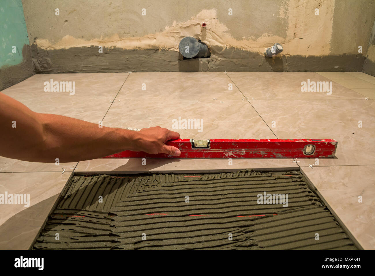 Ceramic tiles and tools for tiler. Worker hand installing floor tiles ...
