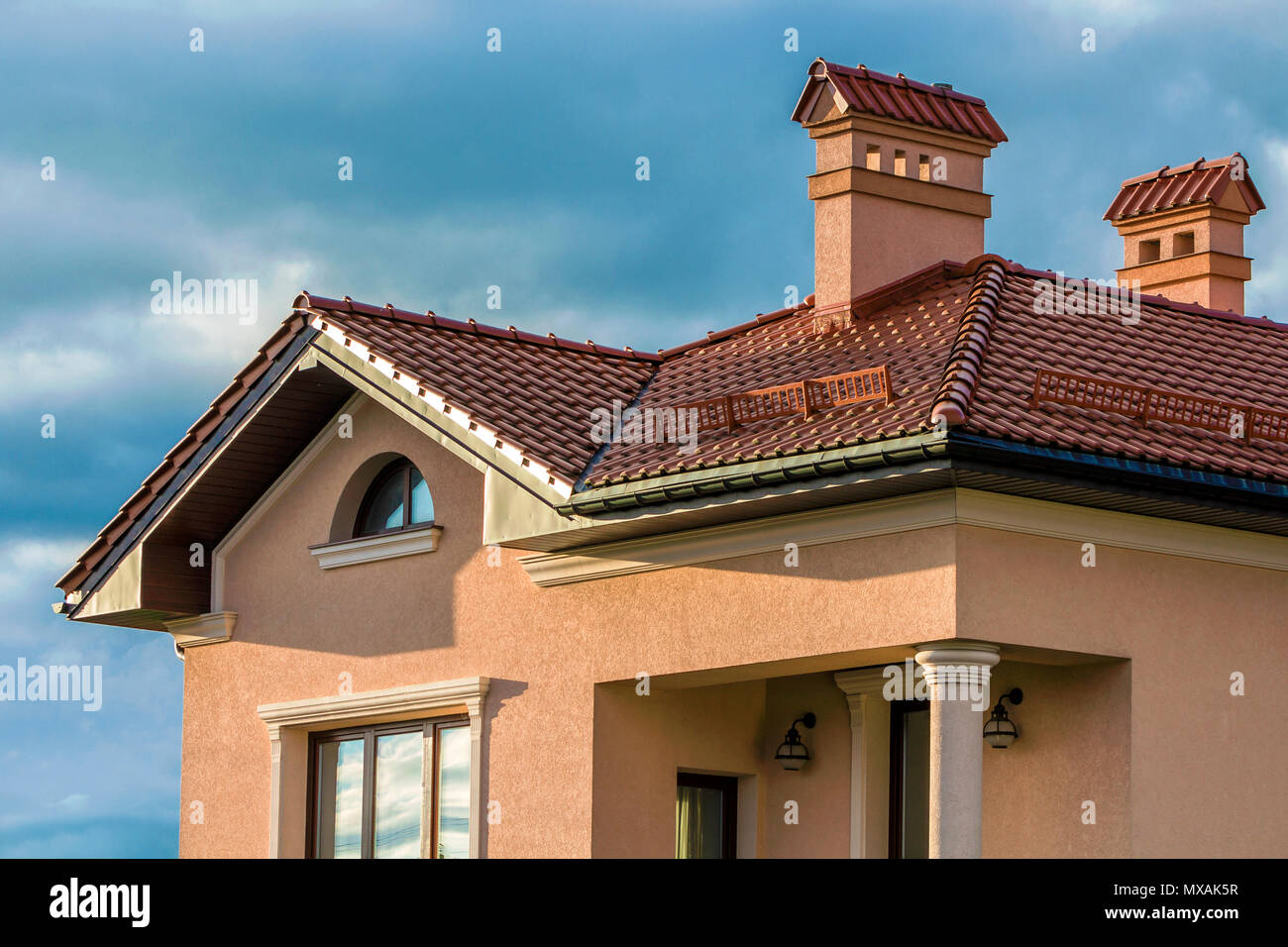 Top of new big modern house with shingled red roof, two high chimneys ...