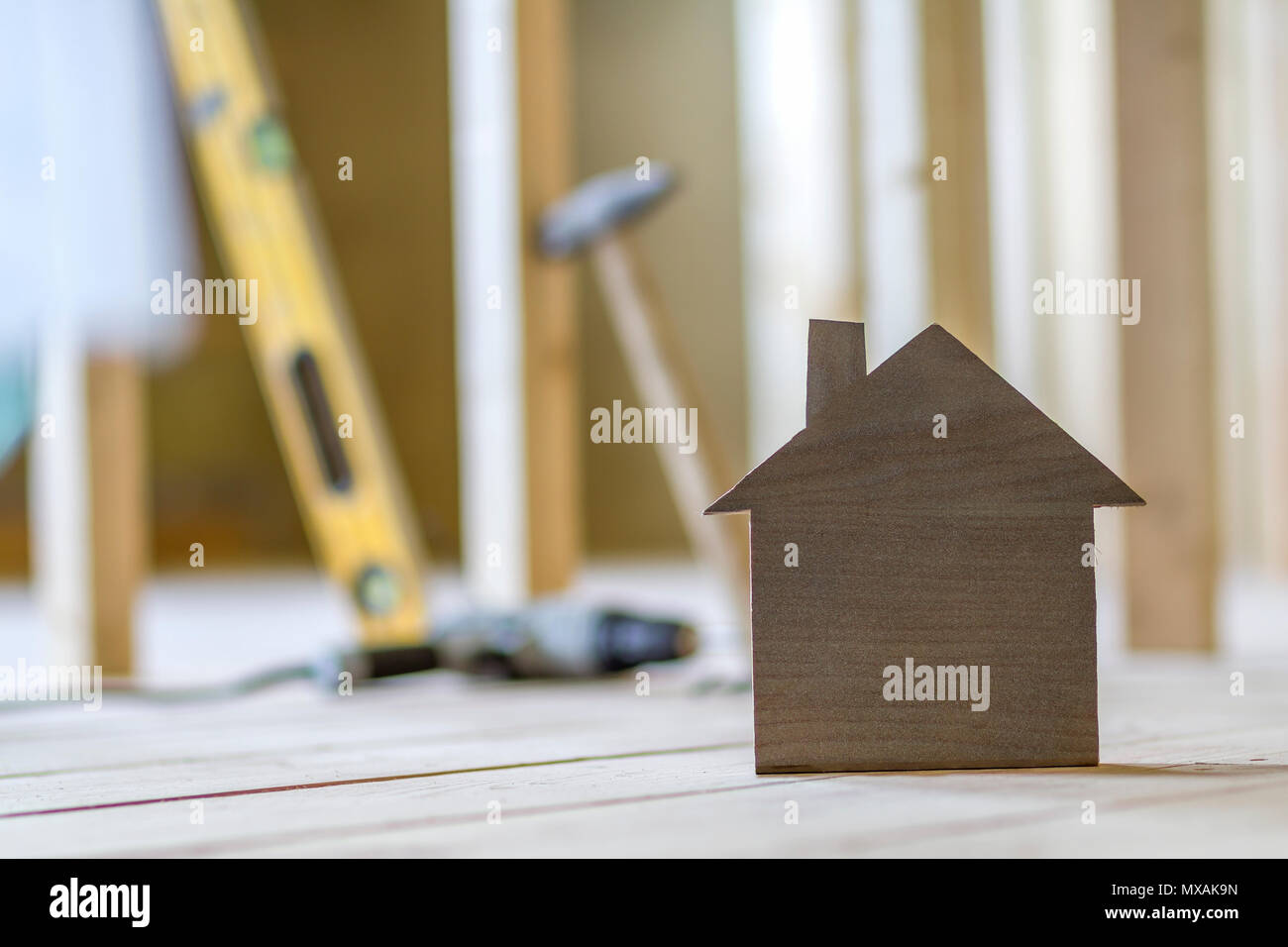 Close-up of simple small brown model house on blurred building tools ...