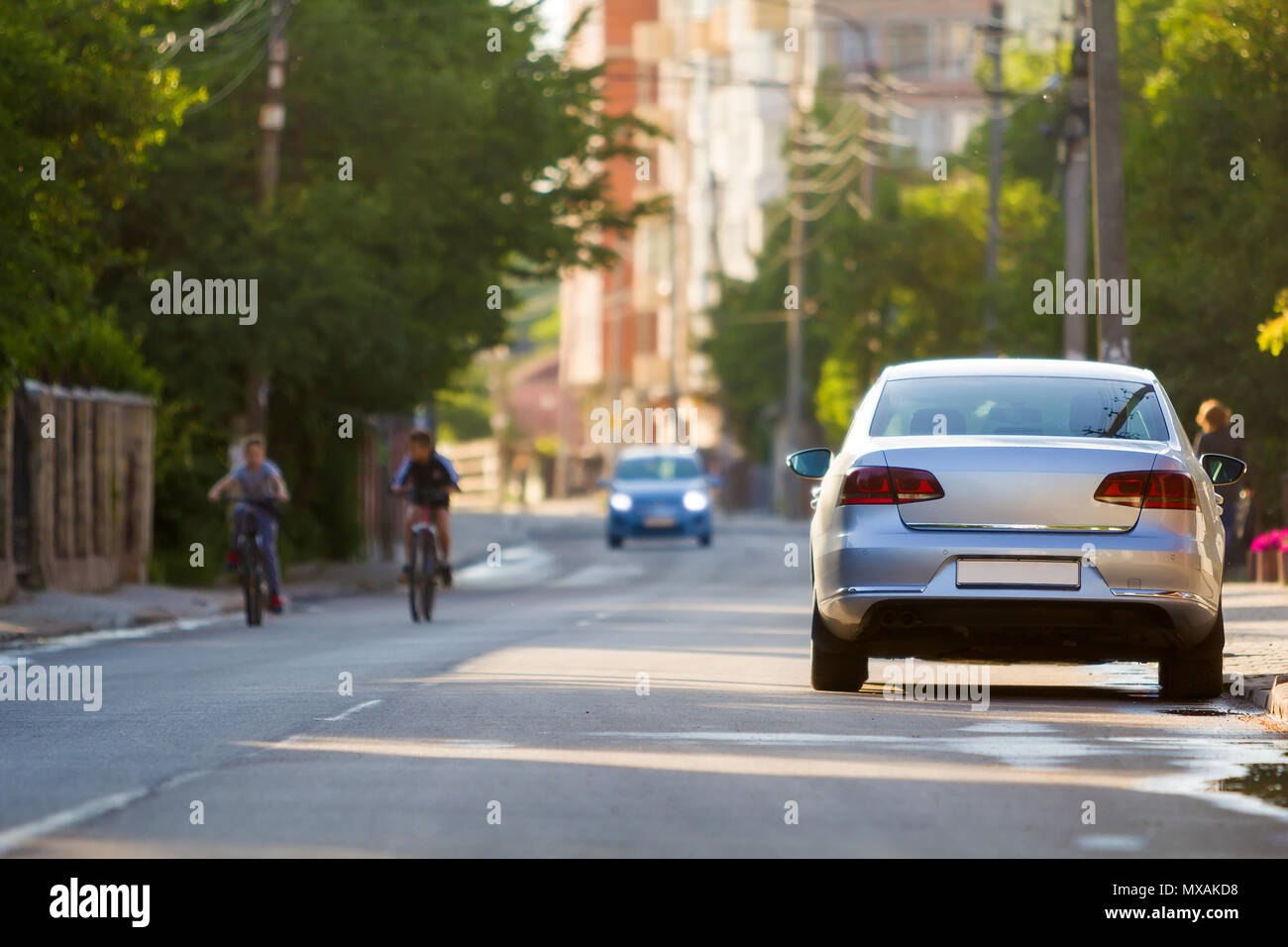 Summer city with two young boys riding bicycles along the street with ...