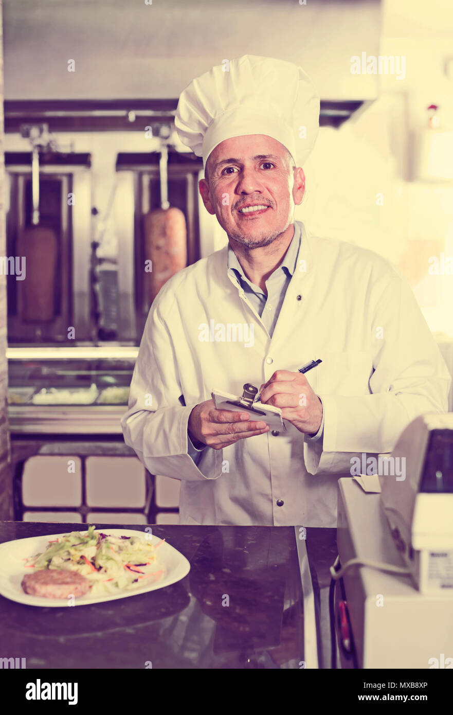 Mature man chef wearing uniform taking order from customer in cafe ...