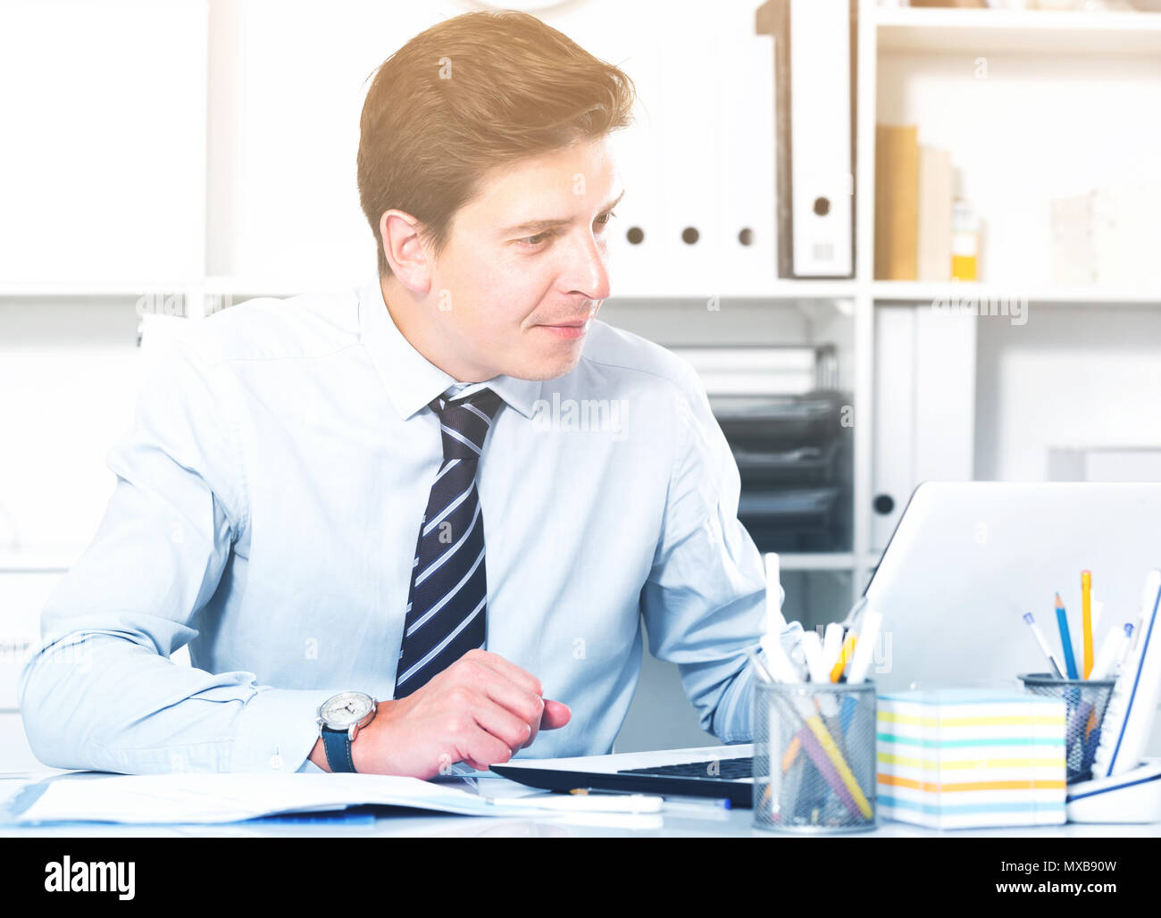 Positive man working effectively in the office at the laptop with ...