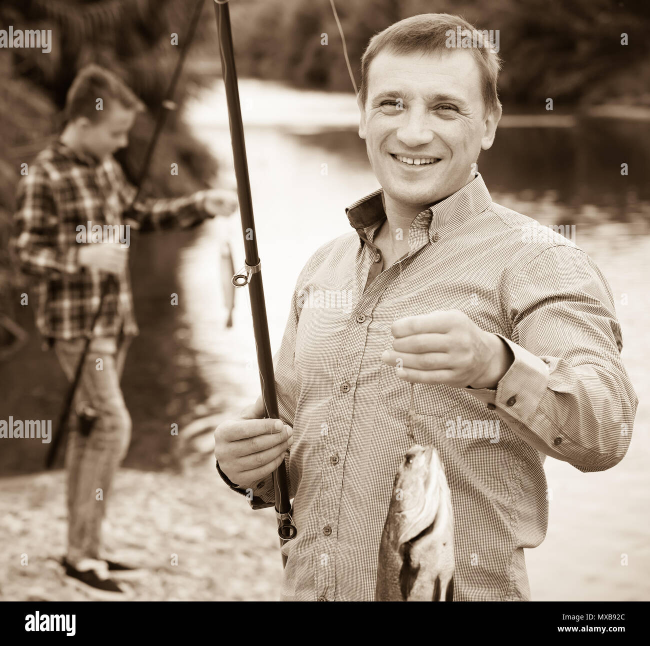 Smiling fisherman holding catch freshwater fish in hands Stock Photo ...