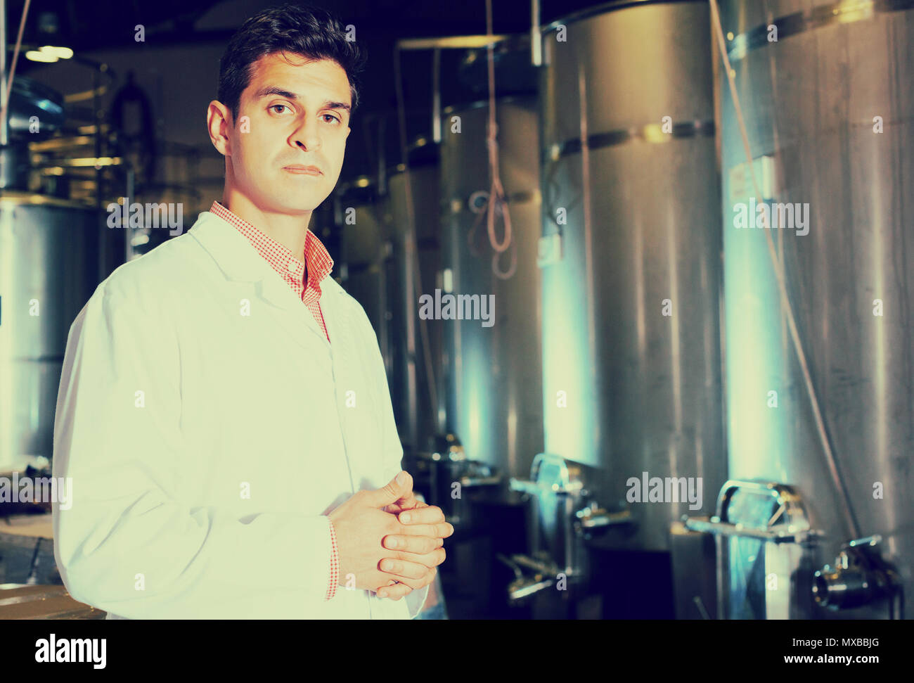 Male winery technician posing with wine in modern cellar Stock Photo ...