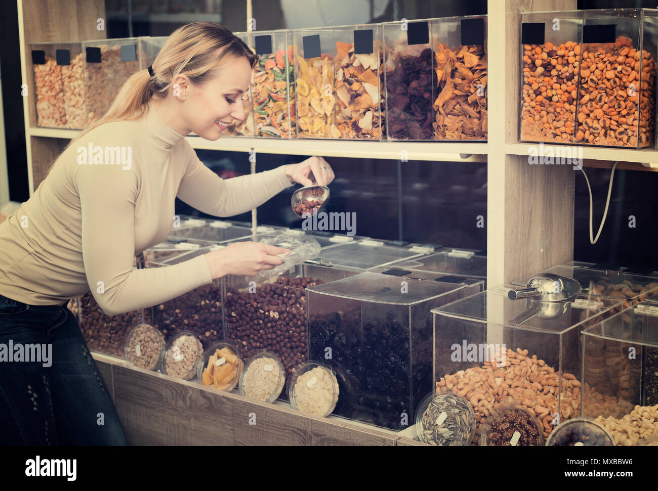 Adult female customer selecting various nuts in the store with ...