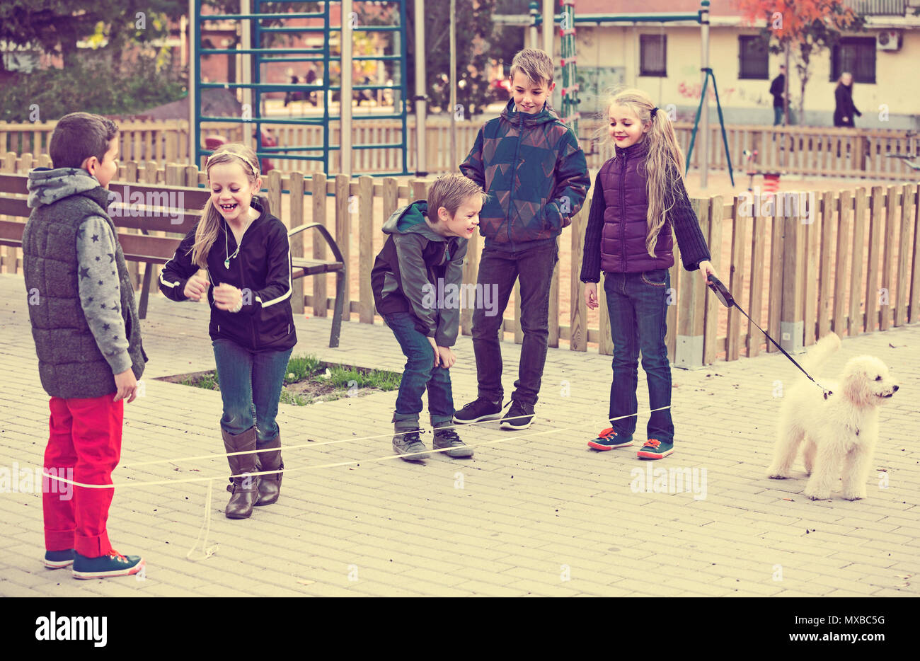 Happy friends playing rubber band jumping game and laughing outdoors ...