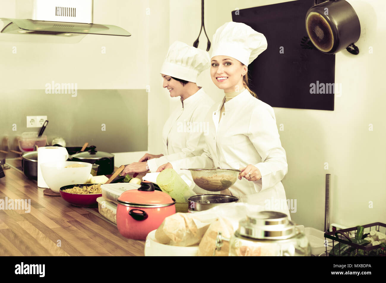 Friendly smiling female chefs preparing food on restaurant kitchen ...