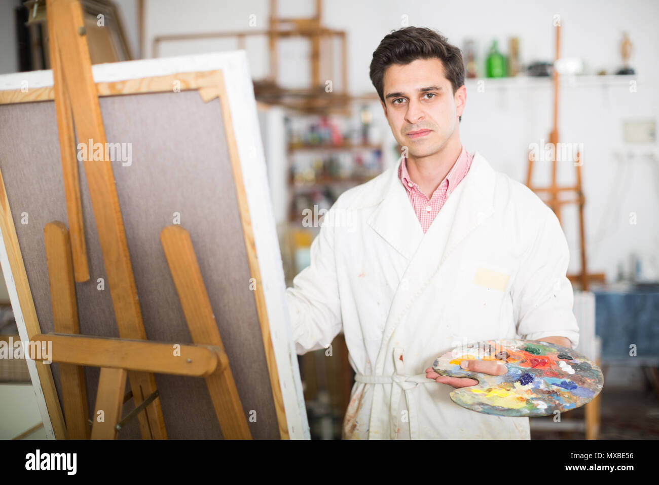 Happy art painter holding artist palette and painting on canvas Stock ...
