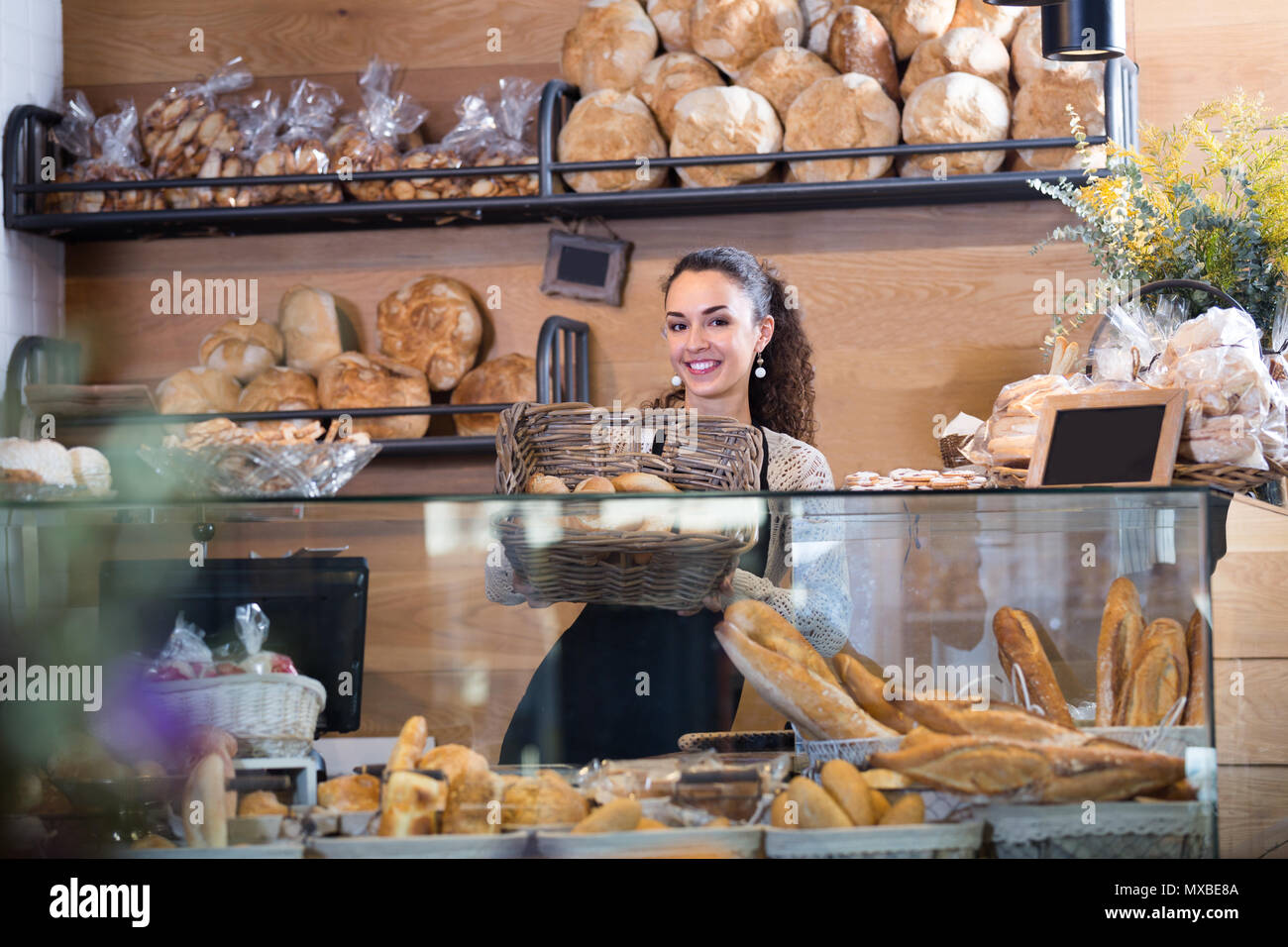 Portrait of friendly young baker at bakery display with pastry Stock ...