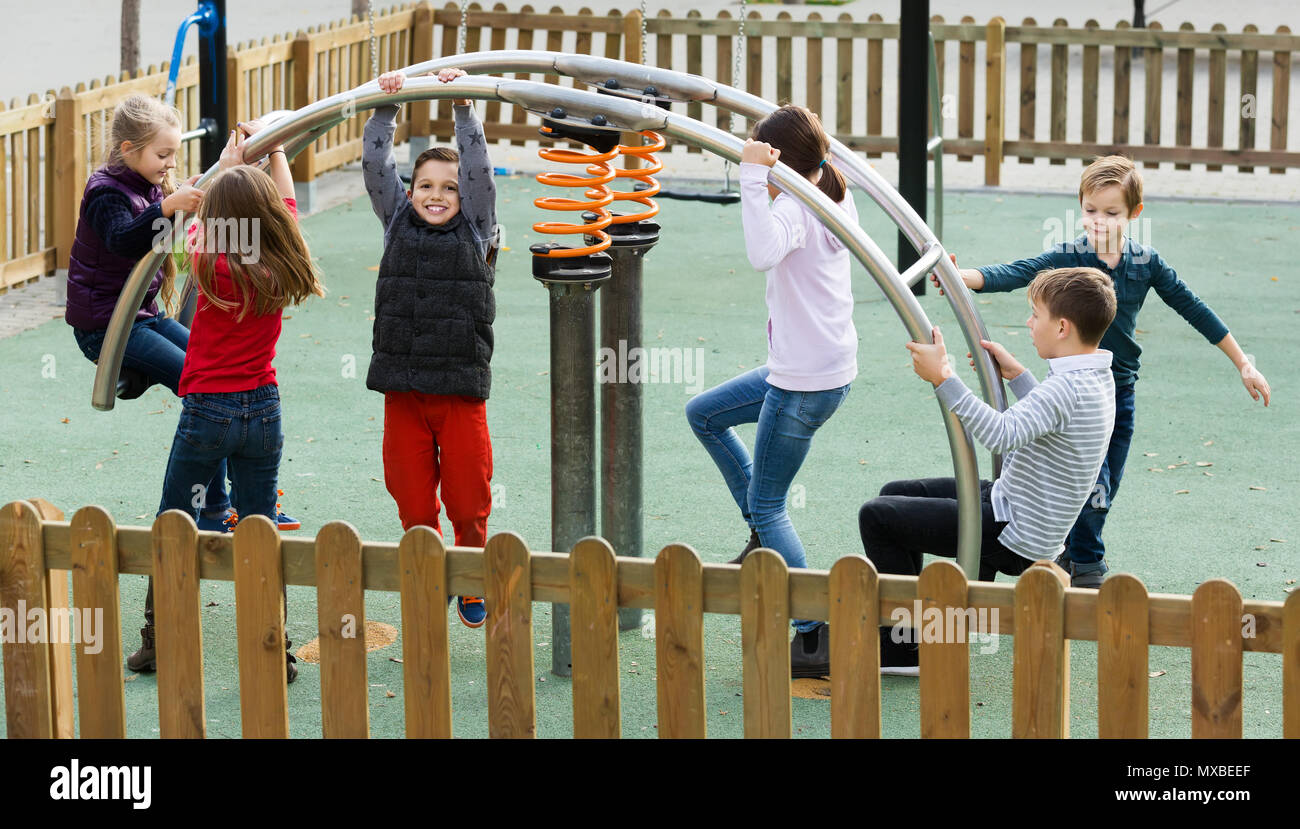 Smiling children playing on swing at playground outdoors Stock Photo ...